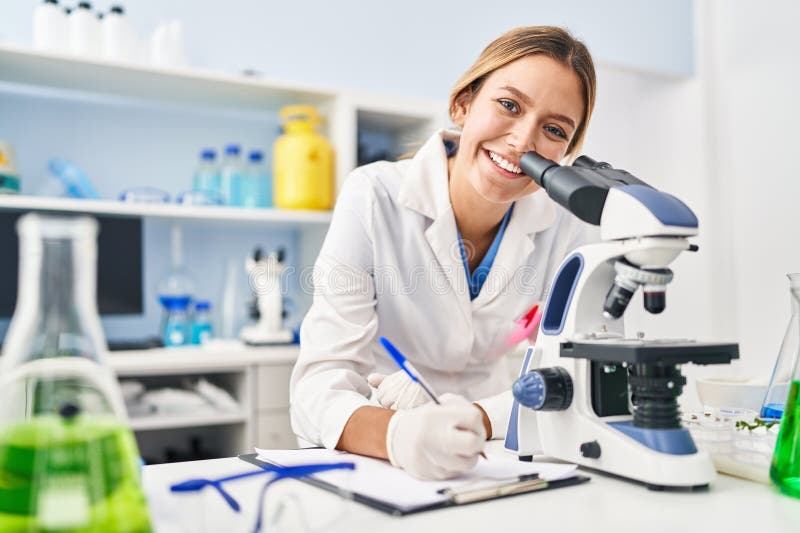 Young Hispanic Woman Scientist Using Microscope Write on Document at ...
