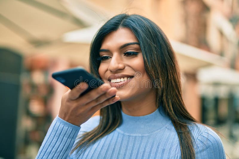 Young Hispanic Woman Sending a Voice Message with Smartphone at the ...