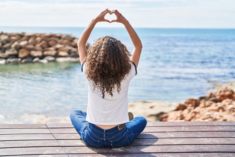 Young Hispanic Woman Sitting on Back View Doing Heart Gesture with ...