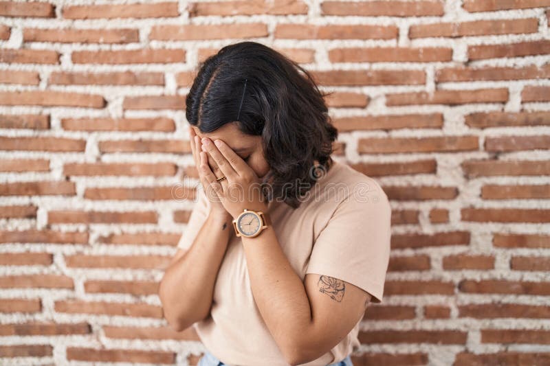 Young Hispanic Woman Standing Over Bricks Wall with Sad Expression ...