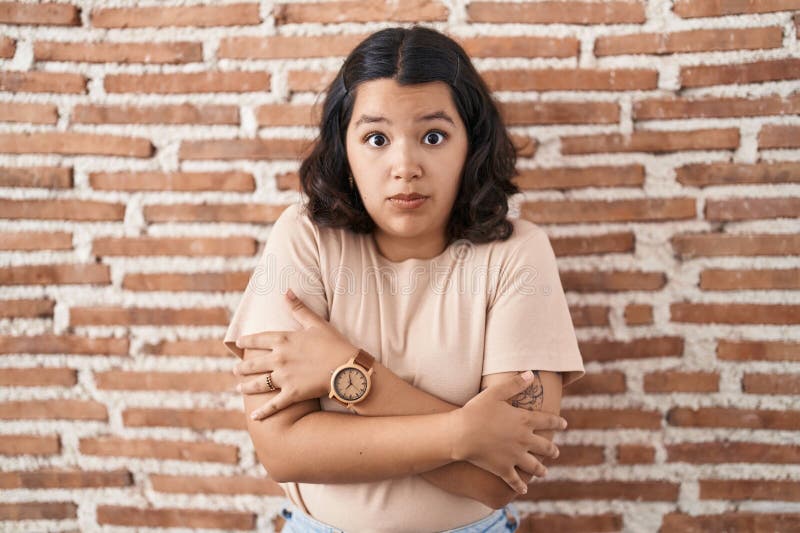 Young Hispanic Woman Standing Over Bricks Wall Shaking and Freezing for ...
