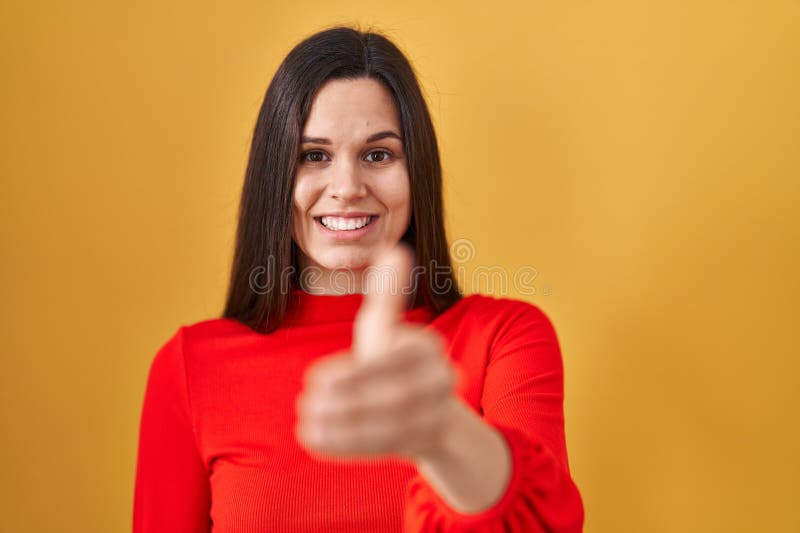 Young Hispanic Woman Standing Over Yellow Background Smiling Friendly ... Young Hispanic Woman Standing Over Yellow Background Smiling Friendly ...