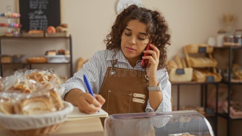 Young Hispanic Woman Talking on the Phone and Writing in a Notebook ...