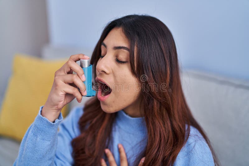 Young Hispanic Woman Using Inhaler Sitting on Sofa at Home Stock Photo ...