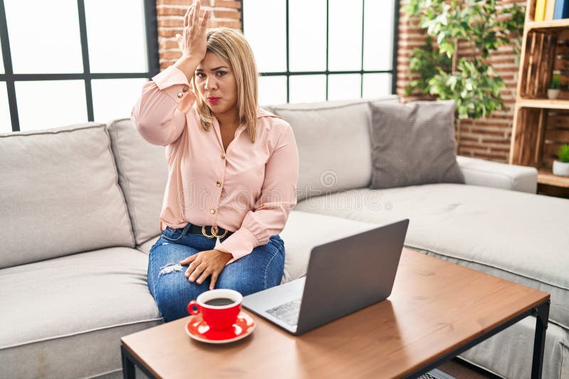 Young Hispanic Woman Using Laptop Sitting On The Sofa At Home Surprised