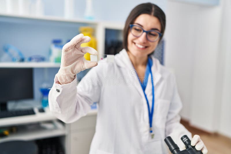 Young Hispanic Woman Wearing Scientist Uniform Using Microscope at ...