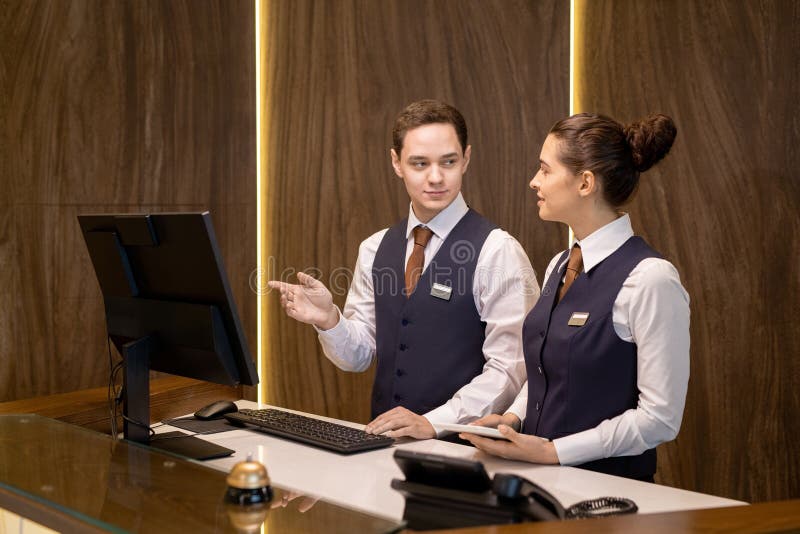 Young Hotel Receptionists Looking at Colleague with Touchpad and ...