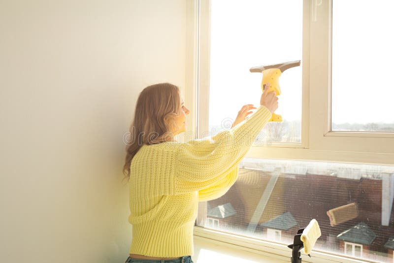Young Housewife in Rays of Setting Sun Uses Device for Washing Windows ...