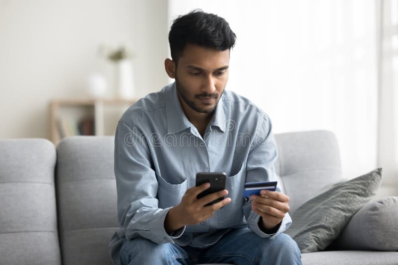Young Indian Guy Buying Online Using Card and Phone Stock Photo - Image ...