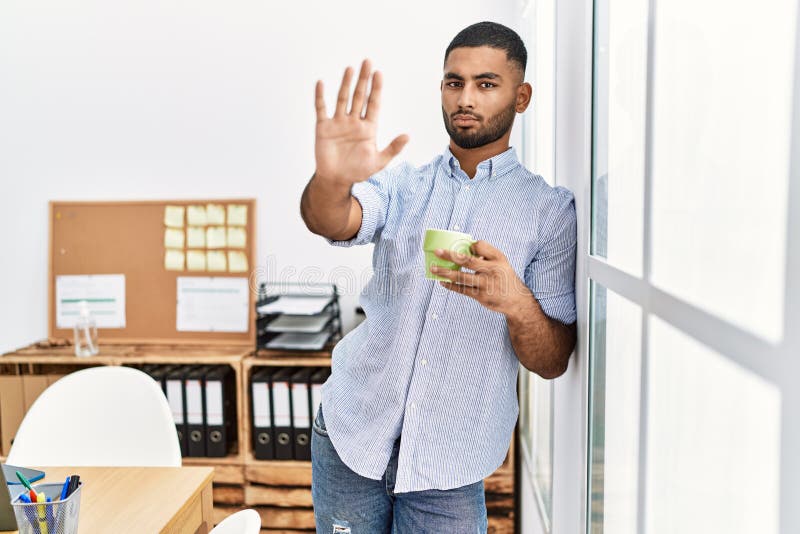 Young Indian Man Drinking a Cup Coffee at the Office with Open Hand ...