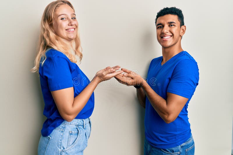 Young Interracial Couple Wearing Casual Clothes Pointing Aside With