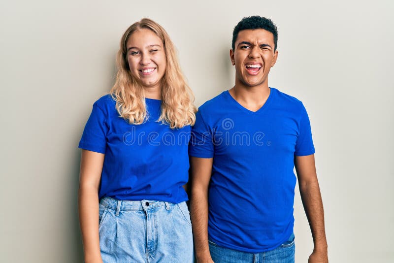 Young Interracial Couple Wearing Casual Clothes Winking Looking At The