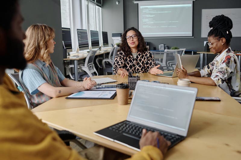 Young Colleagues Discussing it Project Sitting at Table in Office Stock ... Young Colleagues Discussing it Project Sitting at Table in Office Stock ...