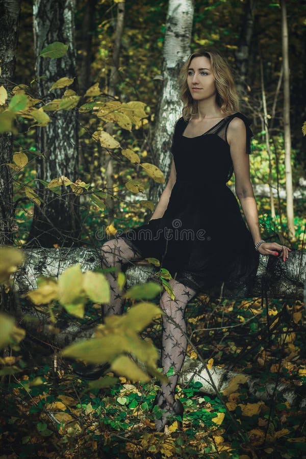 A Young Kind Witch in a Black Dress with a Black Mask in a Mystical ...