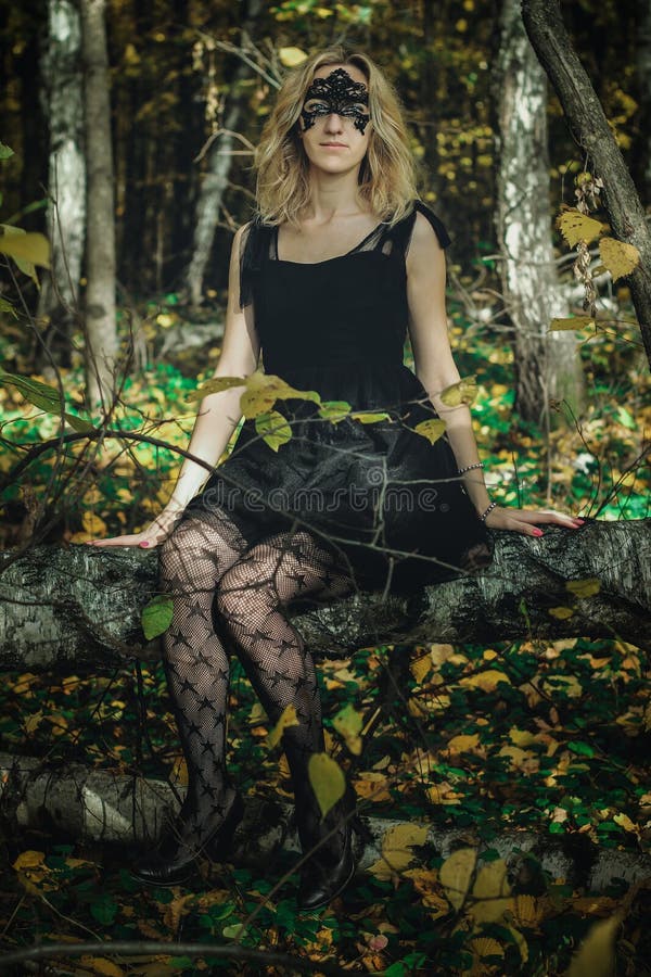 A Young Kind Witch in a Black Dress with a Black Mask in a Mystical ...