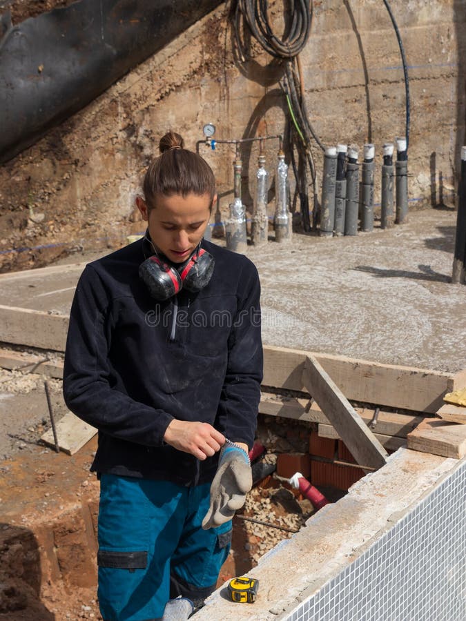 Young Laborer Putting on a Work Glove while Working on a Construction ...