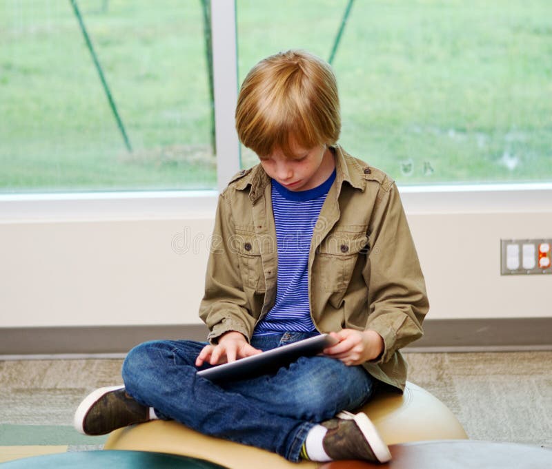 Young lad enjoying tablet stock image. Image of sitting - 51256391