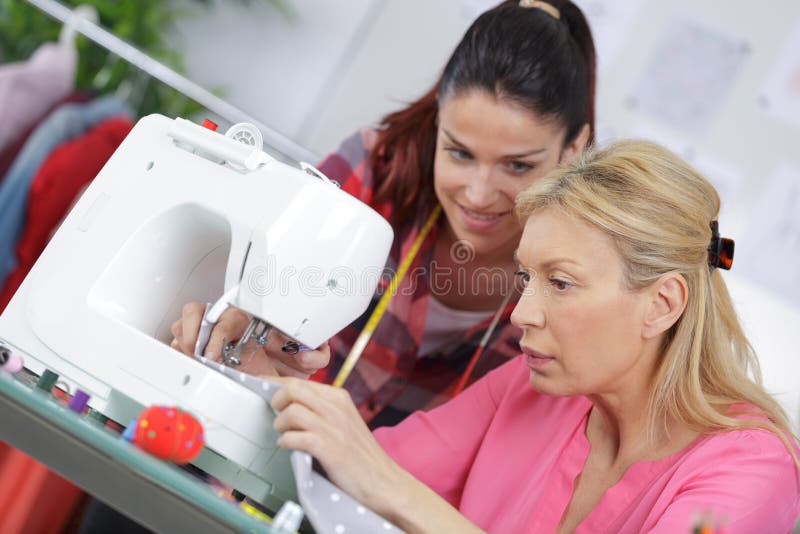 Young Lady Smiles As Older Lady Uses Sewing Machine Stock Image - Image ...