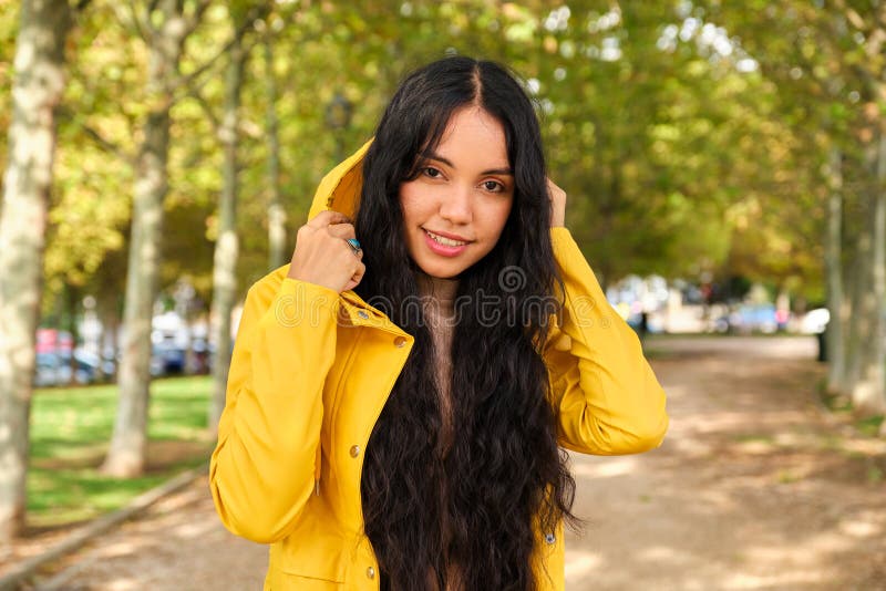 Young Latin Girl Dressed In Yellow Raincoat Posing Looking At Camera
