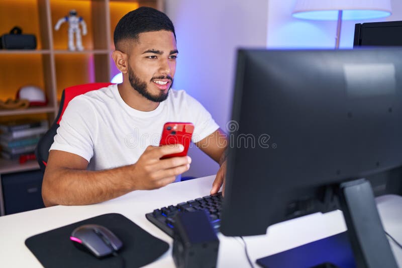 Young Latin Man Streamer Using Computer and Smartphone at Gaming Room ...