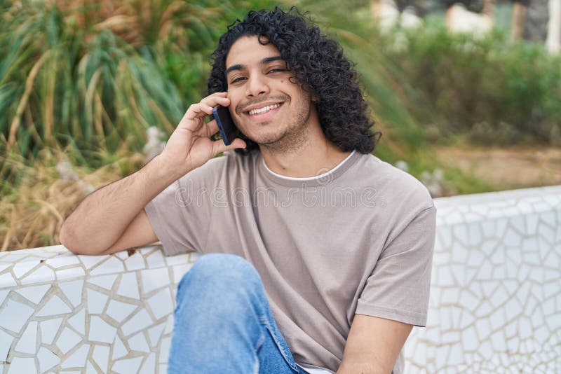 Young Latin Man Talking on the Smartphone Sitting on Bench at Park ...