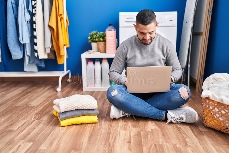 Young Latin Man Using Laptop Waiting for Washing Machine at Laundry ...