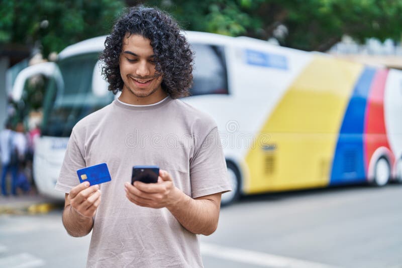 Young Latin Man Using Smartphone and Credit Card at Bus Station Stock ...