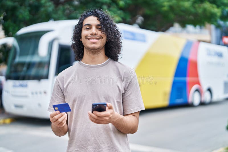 Young Latin Man Using Smartphone and Credit Card at Bus Station Stock ...