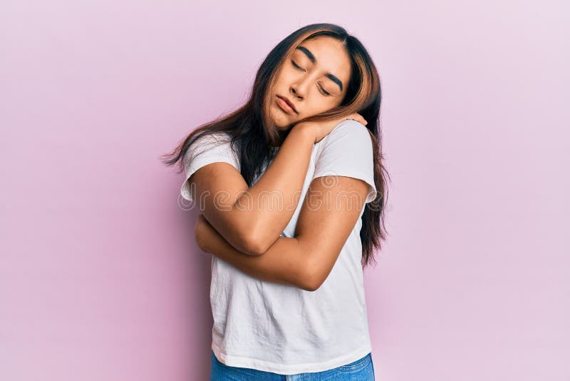 Young Latin Woman Wearing Casual White Tshirt Hugging Oneself Happy And
