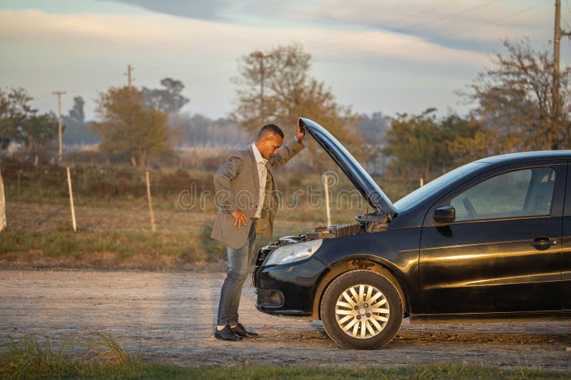 Young Latino Man Dressed in a Suit Looking at the Engine of His Broken ...