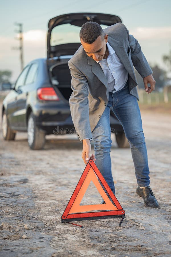 Young Latino Man Placing a Warning Triangle Behind a Broken Down Car ...