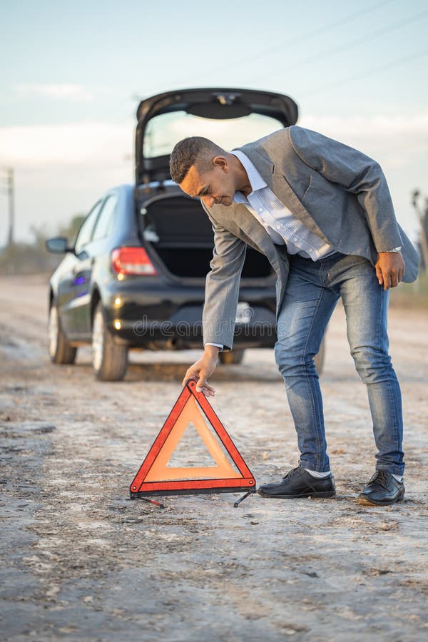 Young Latino Man Placing a Warning Triangle Behind a Broken Down Car Stock Photo - Image of ...