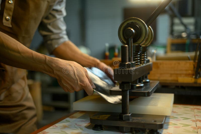Young Leather Craftsman Using a Manual Rolling Machine Working on a ...