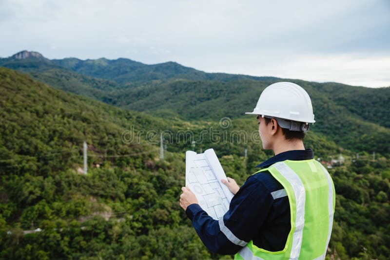 Young Maintenance Engineer Man Working with Blueprint on the Mountain ...