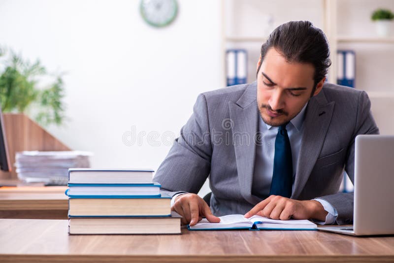Young Male Businessman Reading Books at Workplace Stock Photo - Image ...
