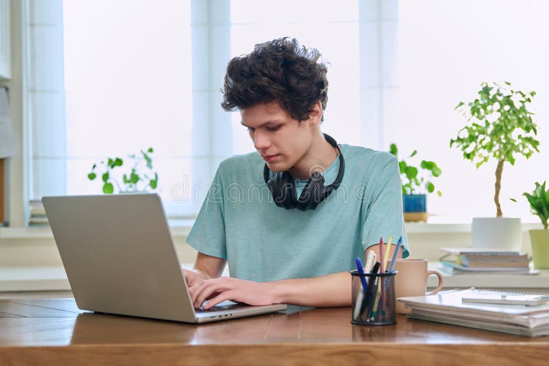 Young Male College Student Sitting at Desk with Laptop Looking at ...