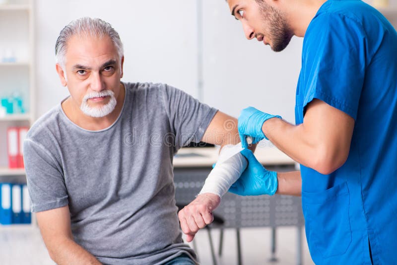 Young Male Doctor and Old Patient in First Aid Concept Stock Image ...