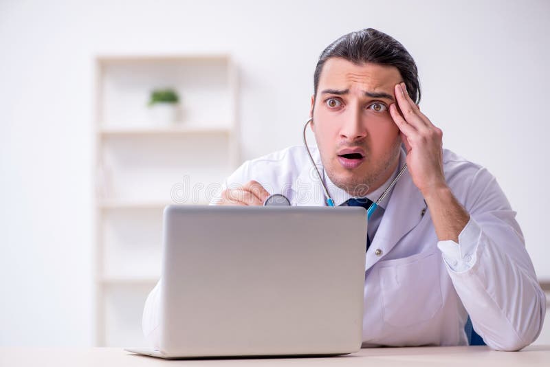 Young Male Doctor with Stethoscope Repairing Computer Stock Photo ...