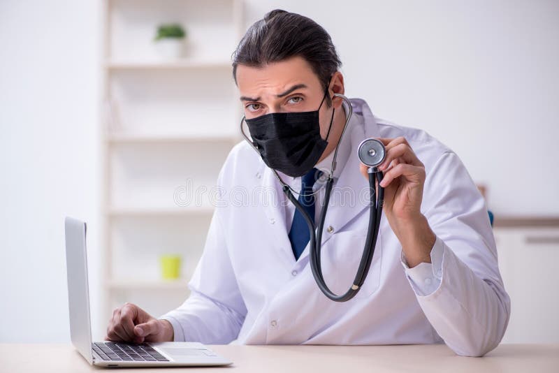 Young Male Doctor with Stethoscope Repairing Computer Stock Photo ...