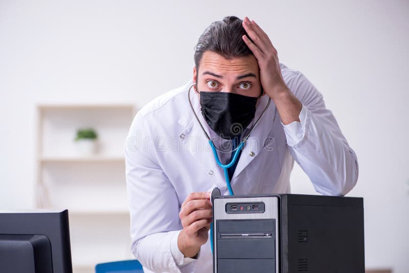 Young Male Doctor with Stethoscope Repairing Computer Stock Photo ...