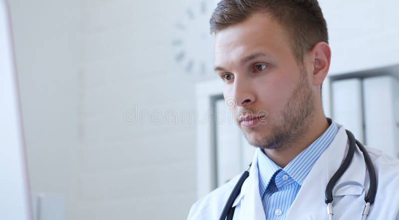 Young Male Doctor Looking at Computer Screen on Desk in Clinic. Stock ...