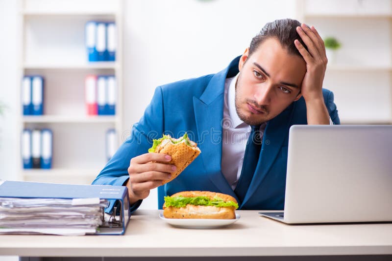 Young Male Employee Having Breakfast at Workplace Stock Photo - Image ...