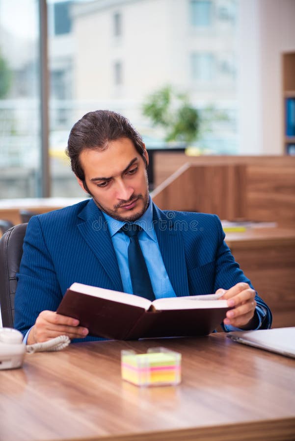 Young Male Employee Reading Book in the Office Stock Photo - Image of ...