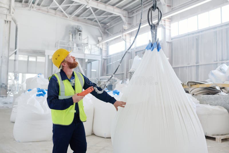 Young Male Engineer Looking Upwards at Huge Hook Where White Sack ...