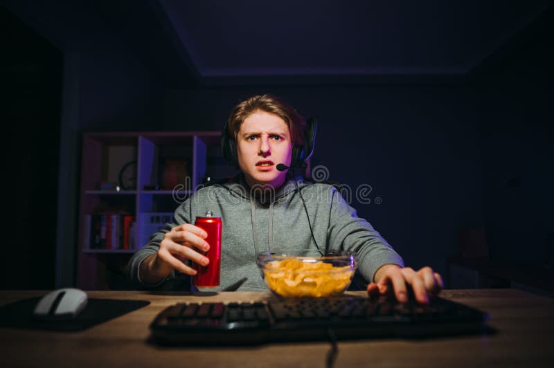 Young Male Gamer Sits at Night at the Computer and Drinks Cola and Eats ...