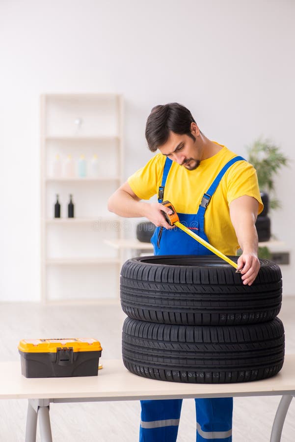 Young Male Garage Worker with Tyre at Workshop Stock Photo - Image of puncture, examining: 229136936