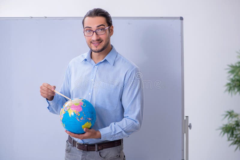 Young Geography Teacher Holding a Globe, Pointing Her Hand at it ...