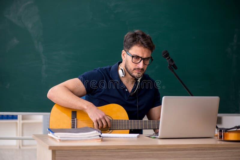Young Male Music Teacher Sitting in the Classroom Stock Image - Image ...