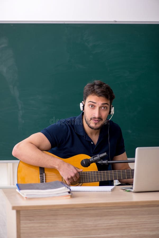 Young Male Music Teacher Sitting in the Classroom Stock Photo - Image ...