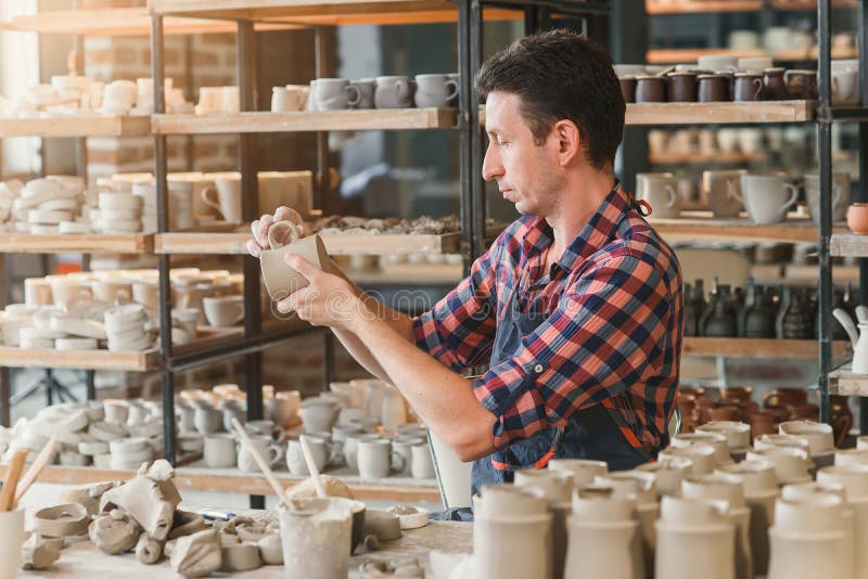 Male Potter Looking To the Handmade Cap during Work Day in the Pottery ...